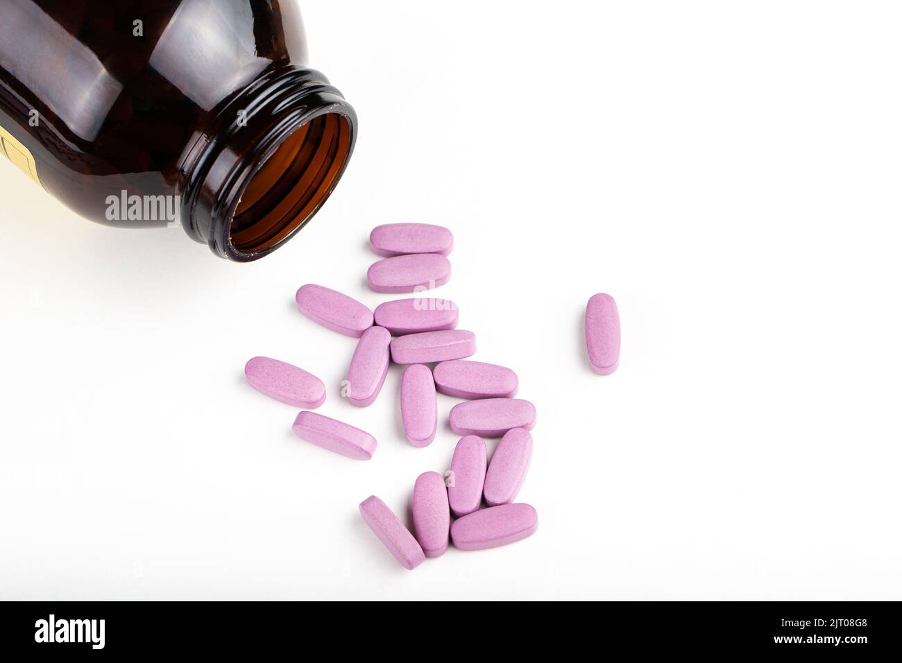 Pink medical pills and tablets spilling out of a drug bottle ...