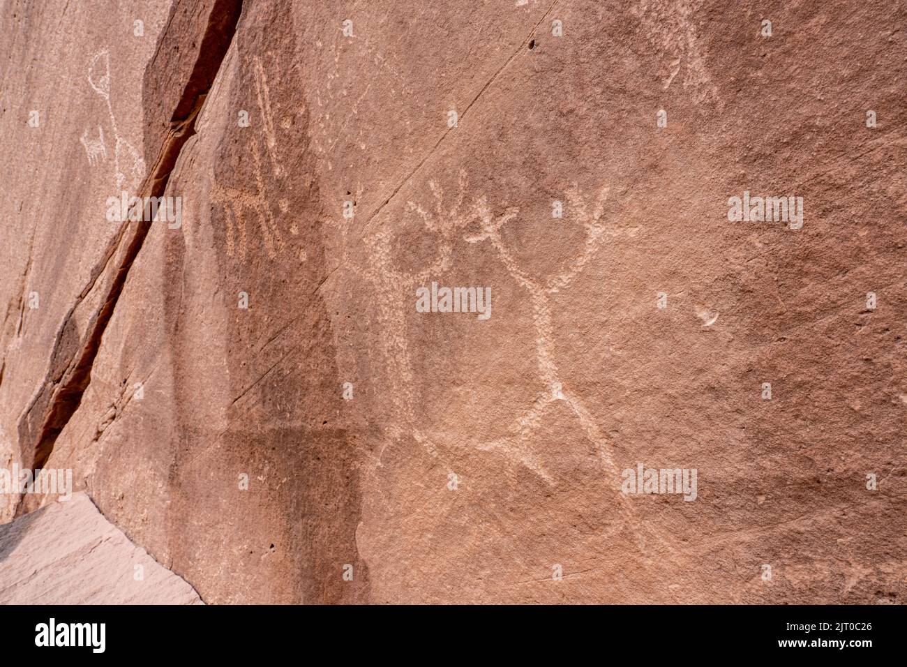 People and animal figures pecked into the sandstone wall of the ...