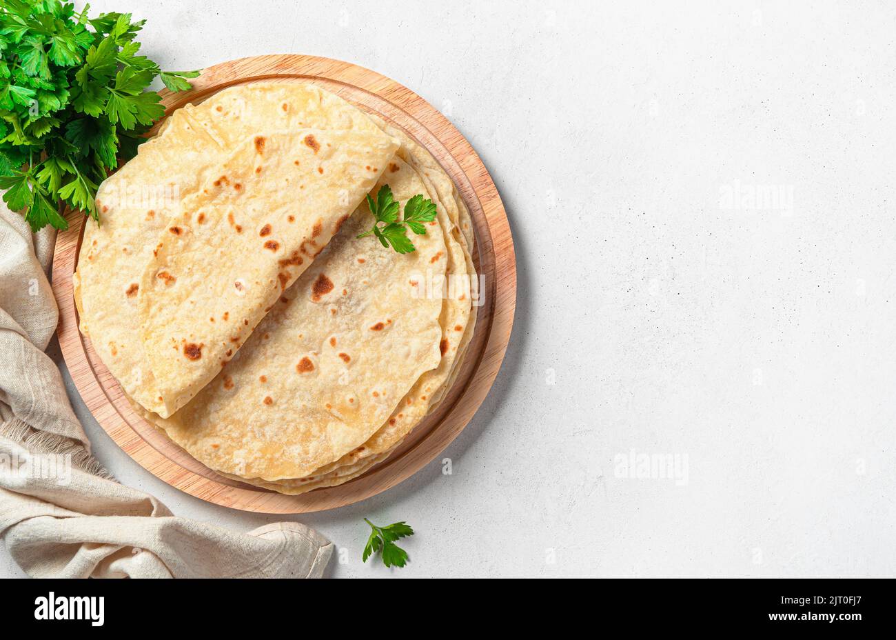 Traditional Indian chapati cakes on a wooden board with fresh herbs on ...