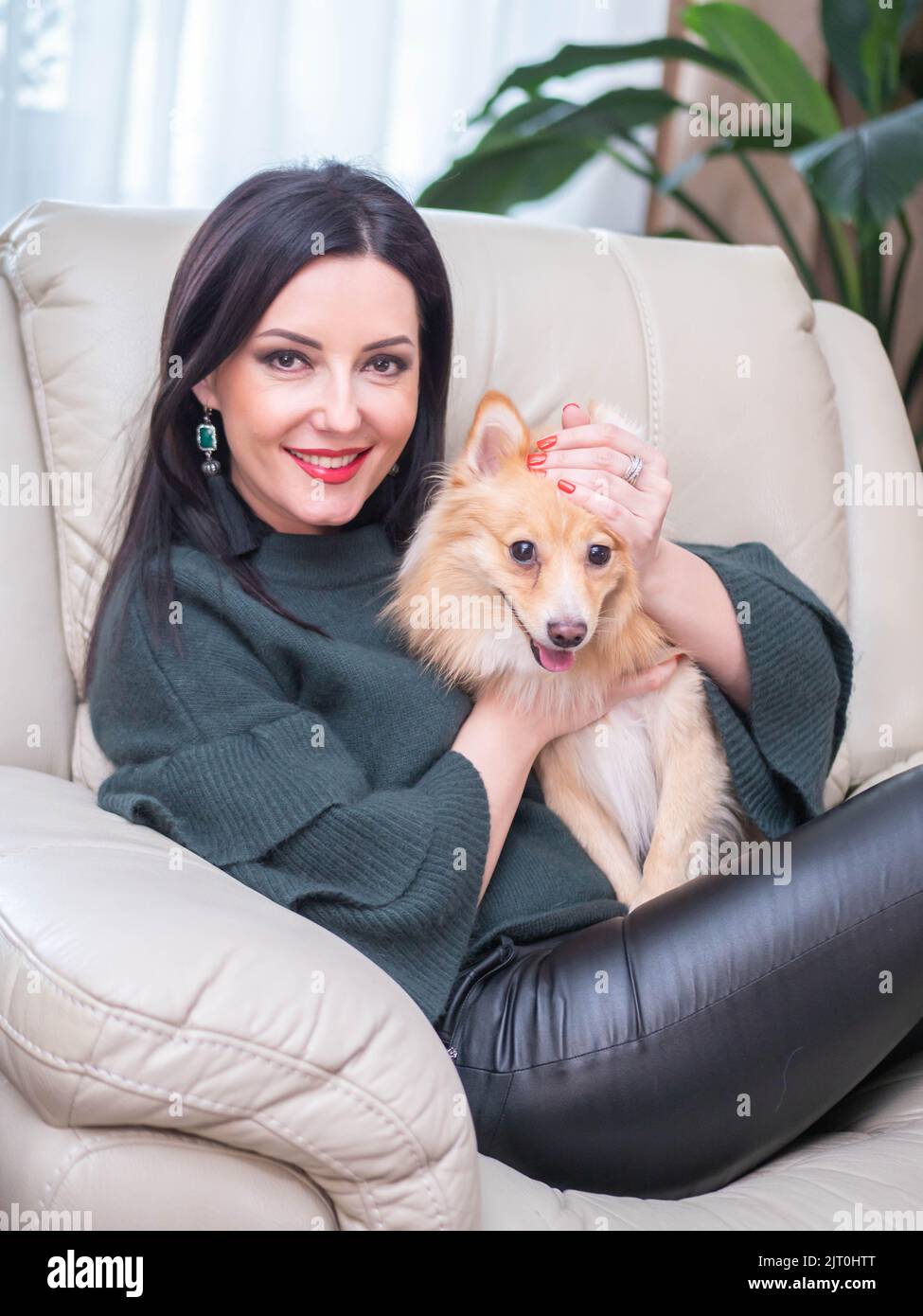 Portrait of mature beautiful woman sitting at home with her lovely pet ...