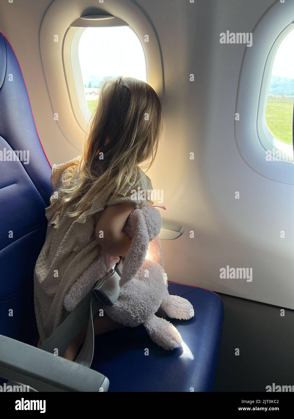 Little girl looks out the window of an airplane. Back view Stock Photo ...