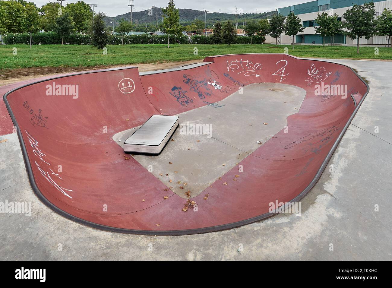 Concrete skate park skate park empty, with trees some graffiti and ...