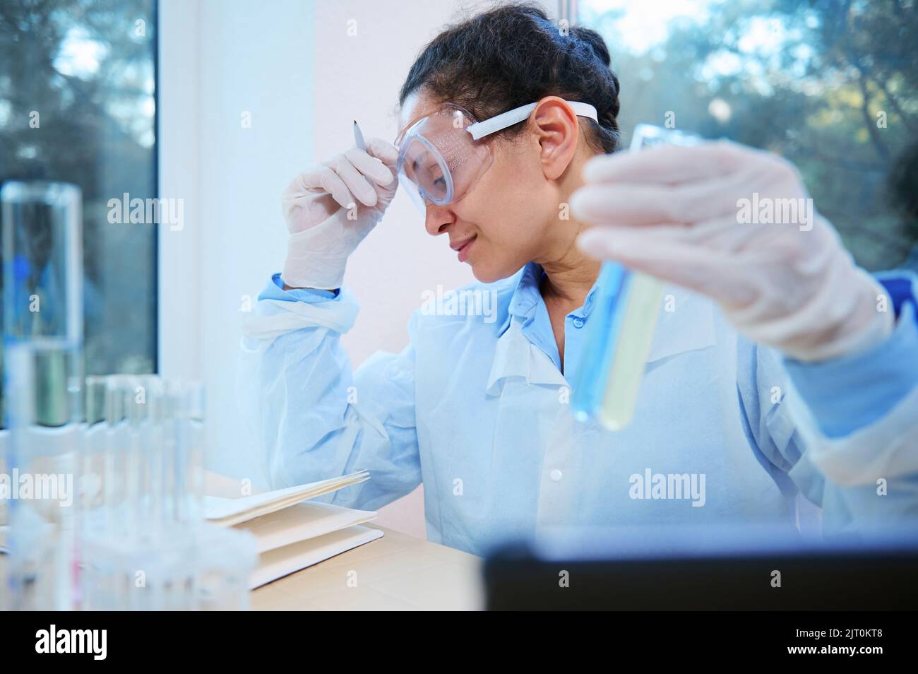 Female scientist pharmacologist holds test tube with blue liquid ...