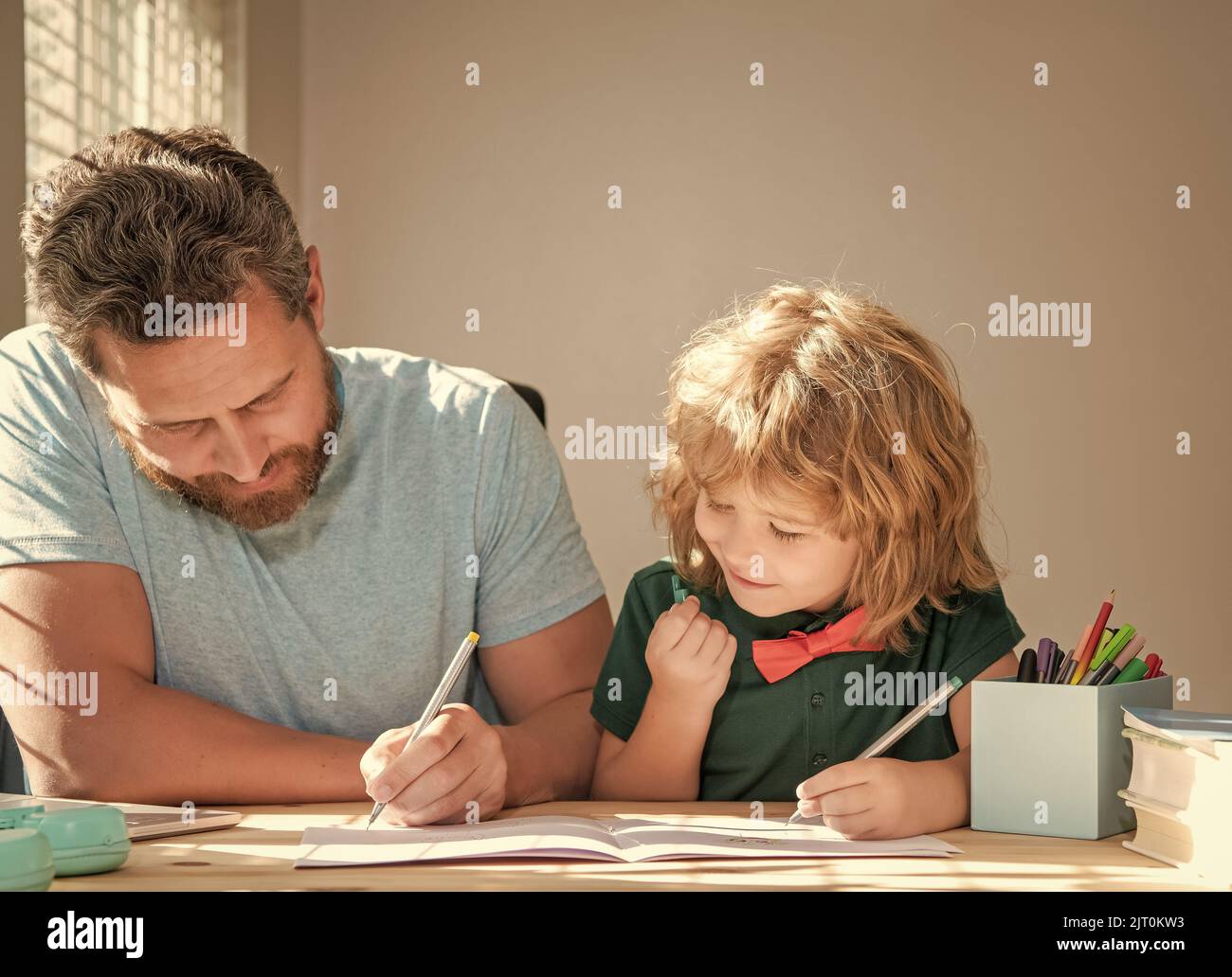 parenthood. concentrated father and son writing at home. family day ...