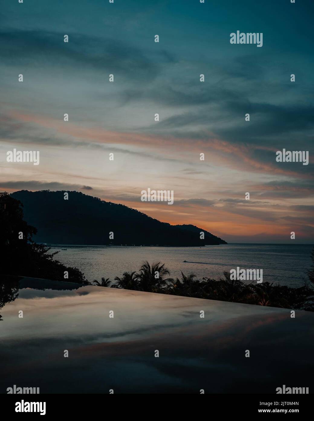 A swimming pool overlooking the ocean at scenic sunset on Penang Island ...