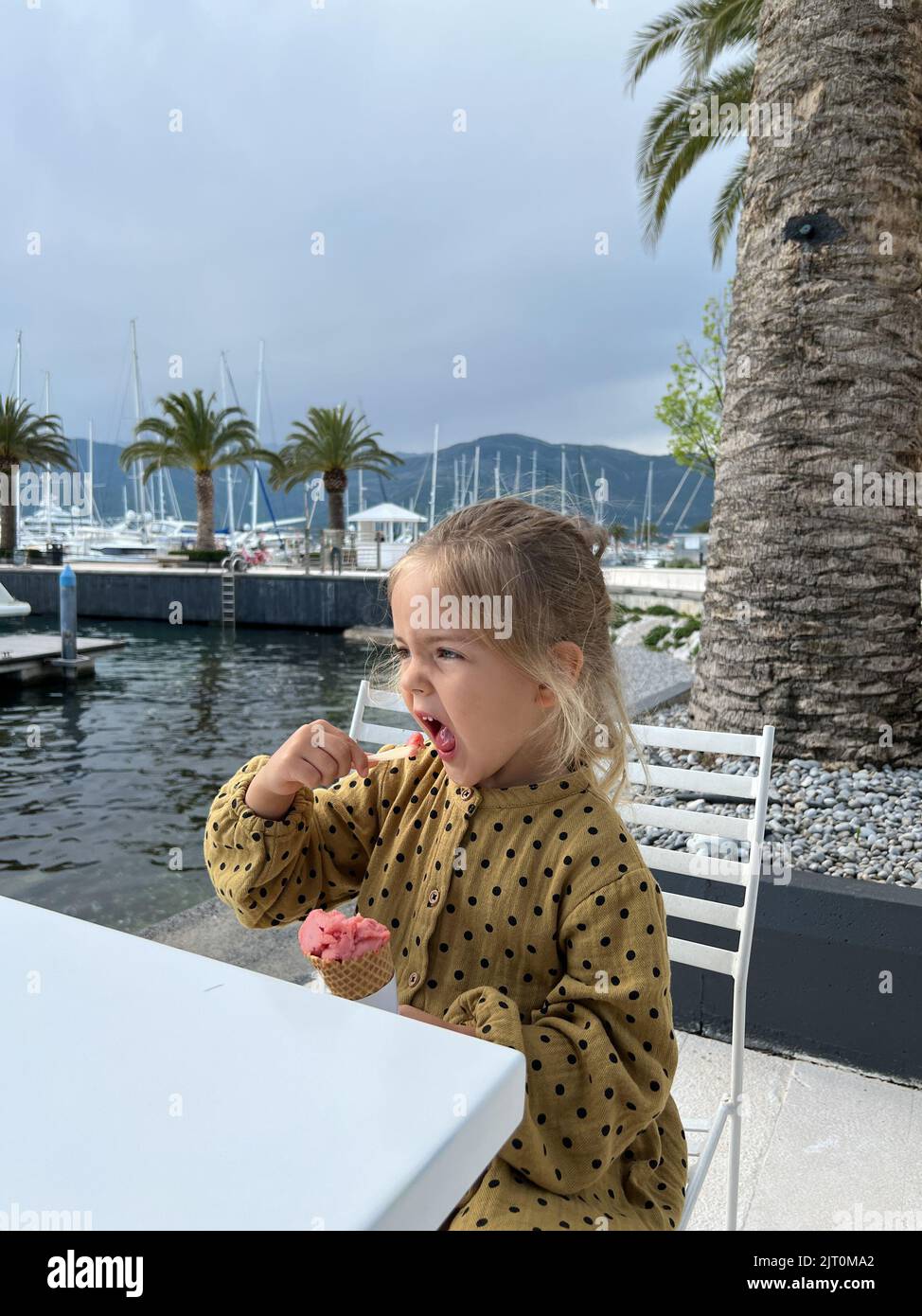 Little girl eating ice cream with a spoon at the table Stock Photo - Alamy