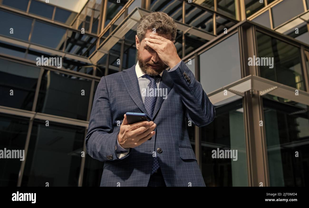 nervous entrepreneur in businesslike suit looking at phone outside the ...