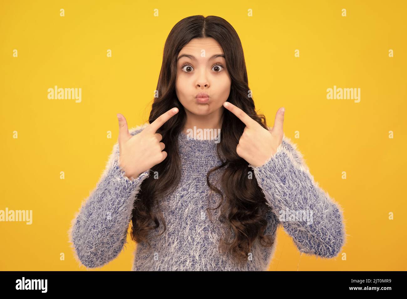 Funny face. Beautiful teen child pinching cheeks with index finger ...