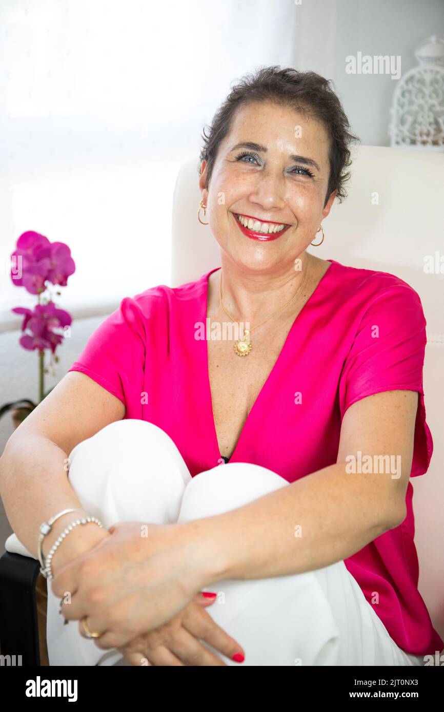A vertical shot of a 50-year-old cancer overcomer sitting on the sofa ...