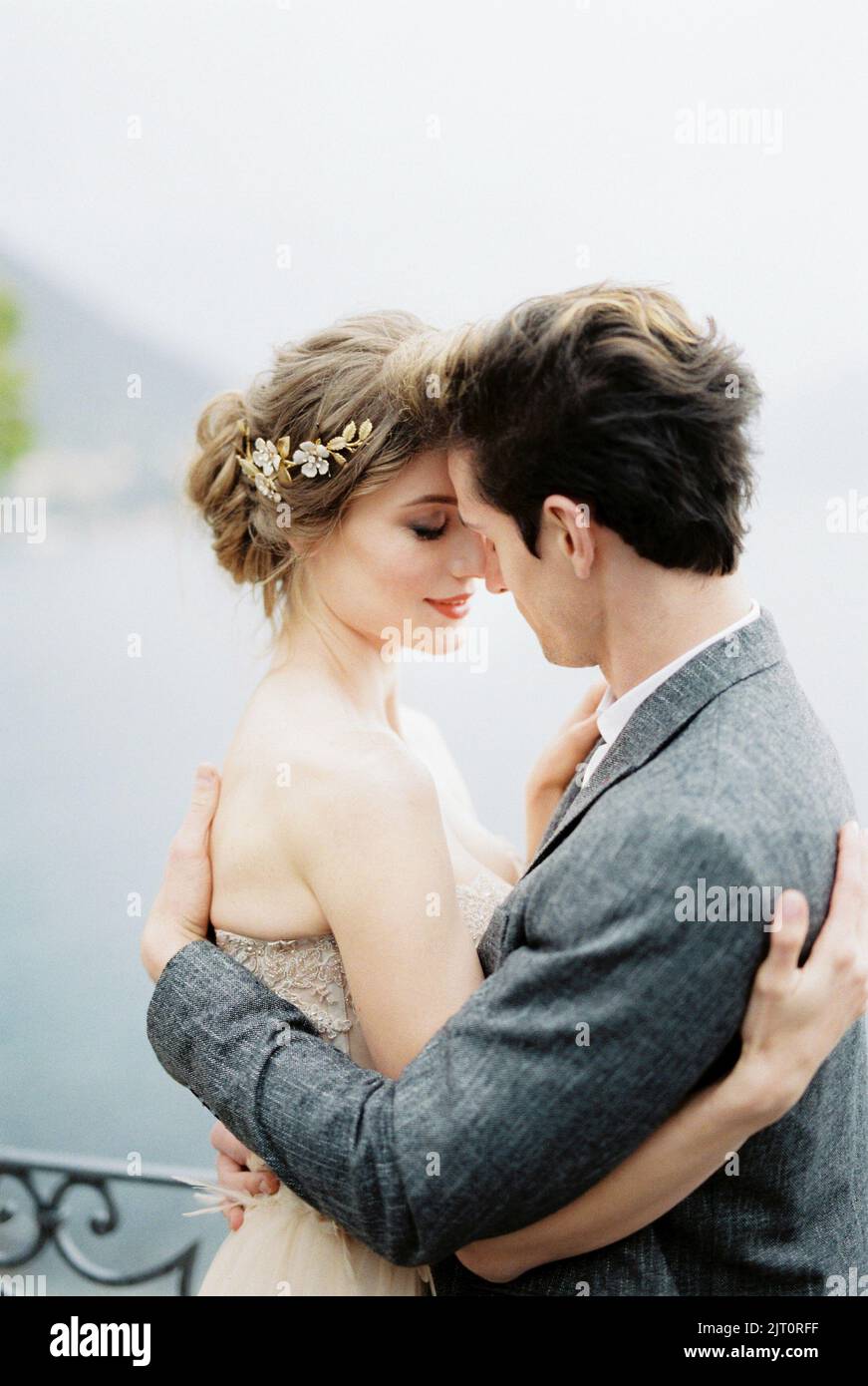 Bride and groom hug each other with their foreheads touching. Portrait ...