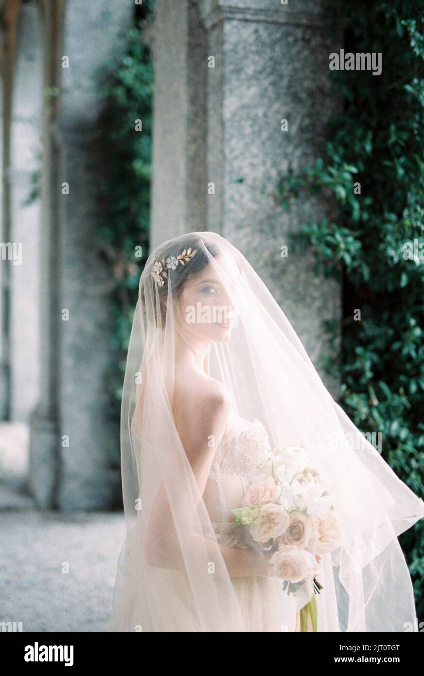 Bride in a dress with a veil stands near the pillar. Portrait Stock ...