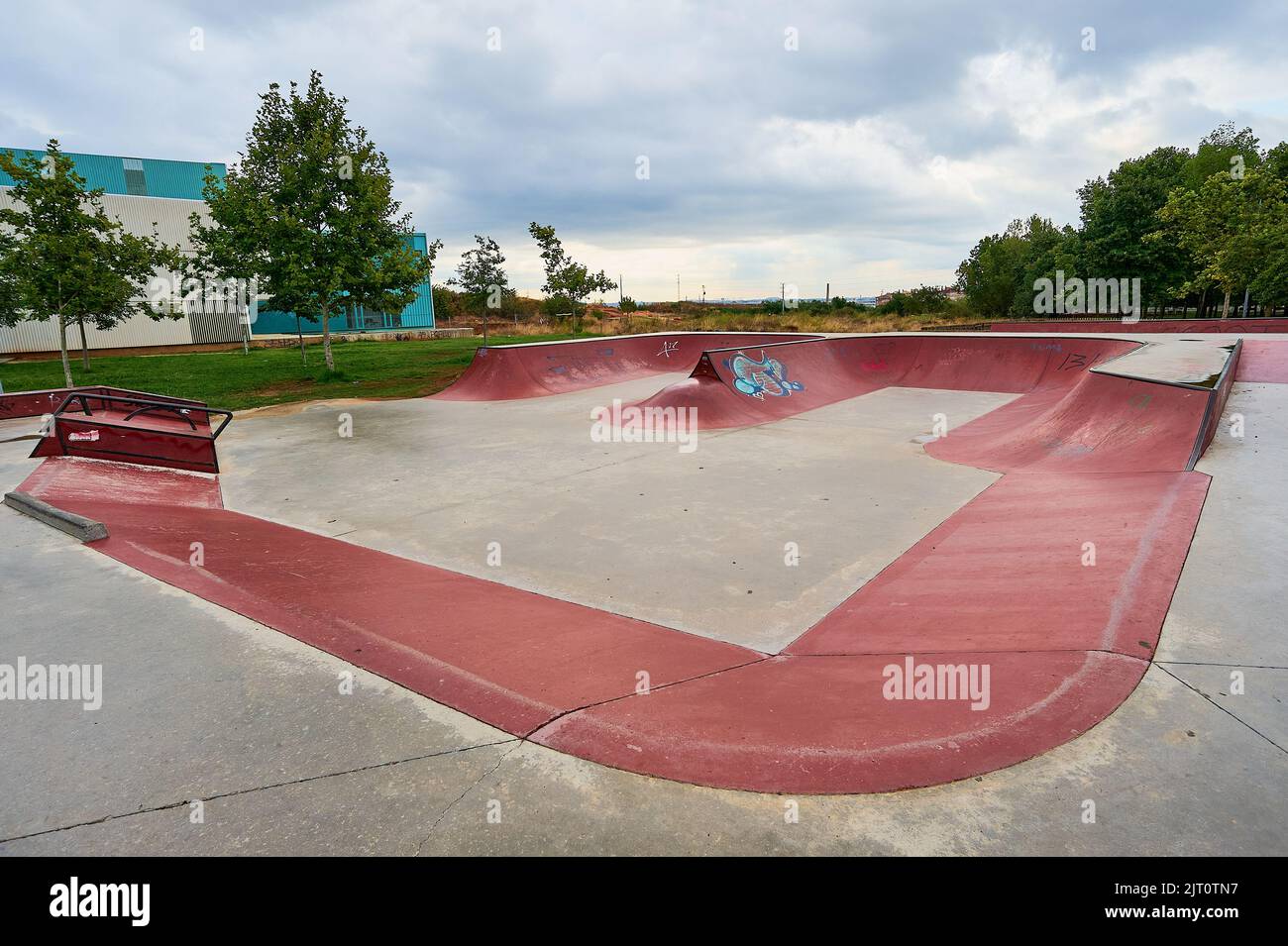 Concrete skate park skate park empty, with trees some graffiti and ...
