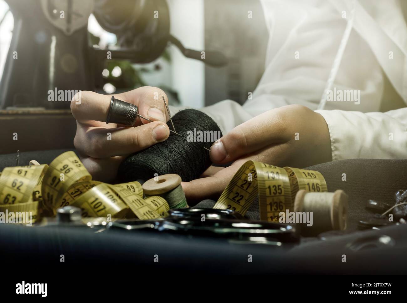 The tailor's hands sew clothes with a needle and thread. Tools for a ...