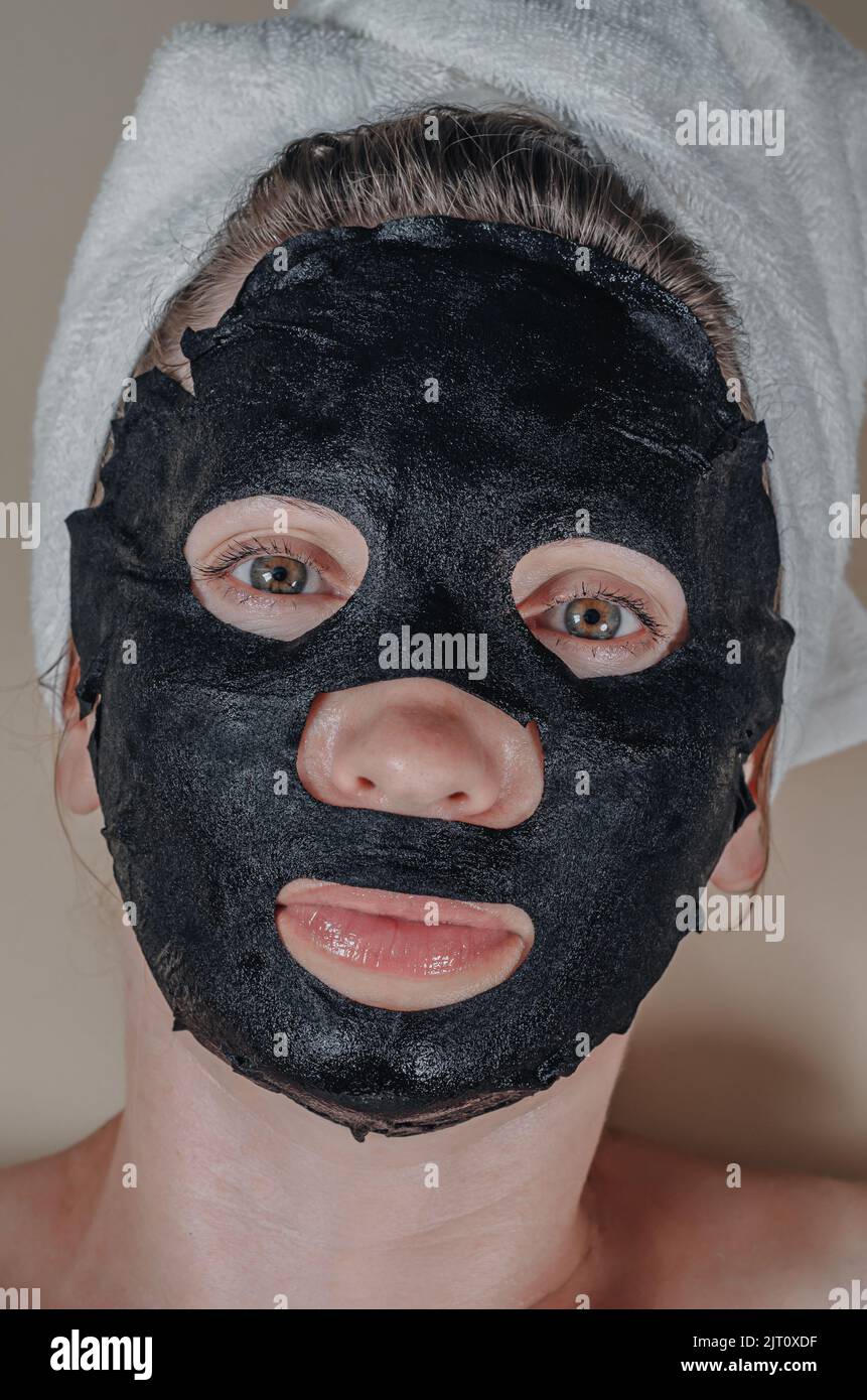 Black cosmetic fabric mask on woman's face. Face peeling mask with coal ...