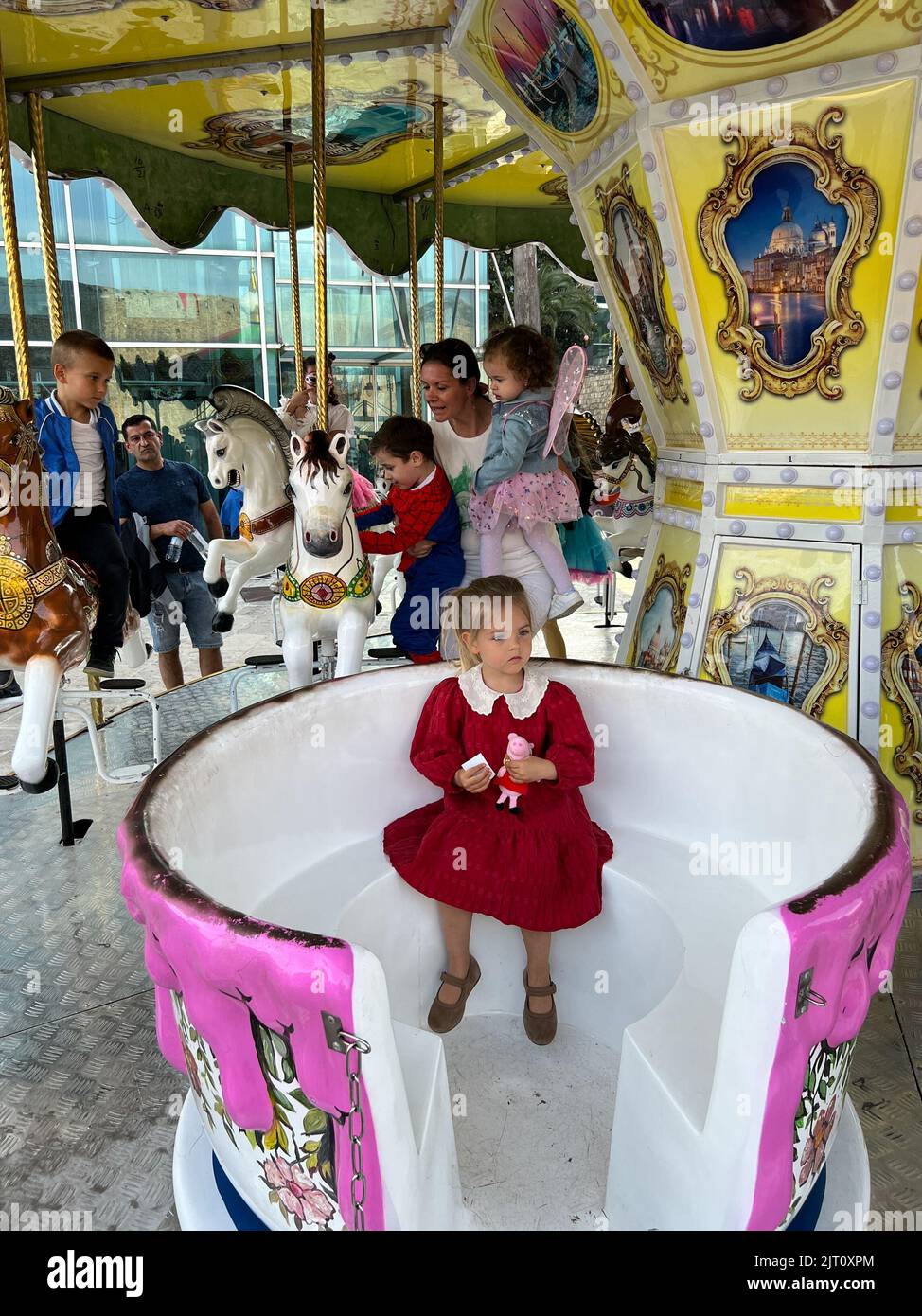 Budva, Montenegro - 12.07.22: Little girl sits in a cup carousel on ...