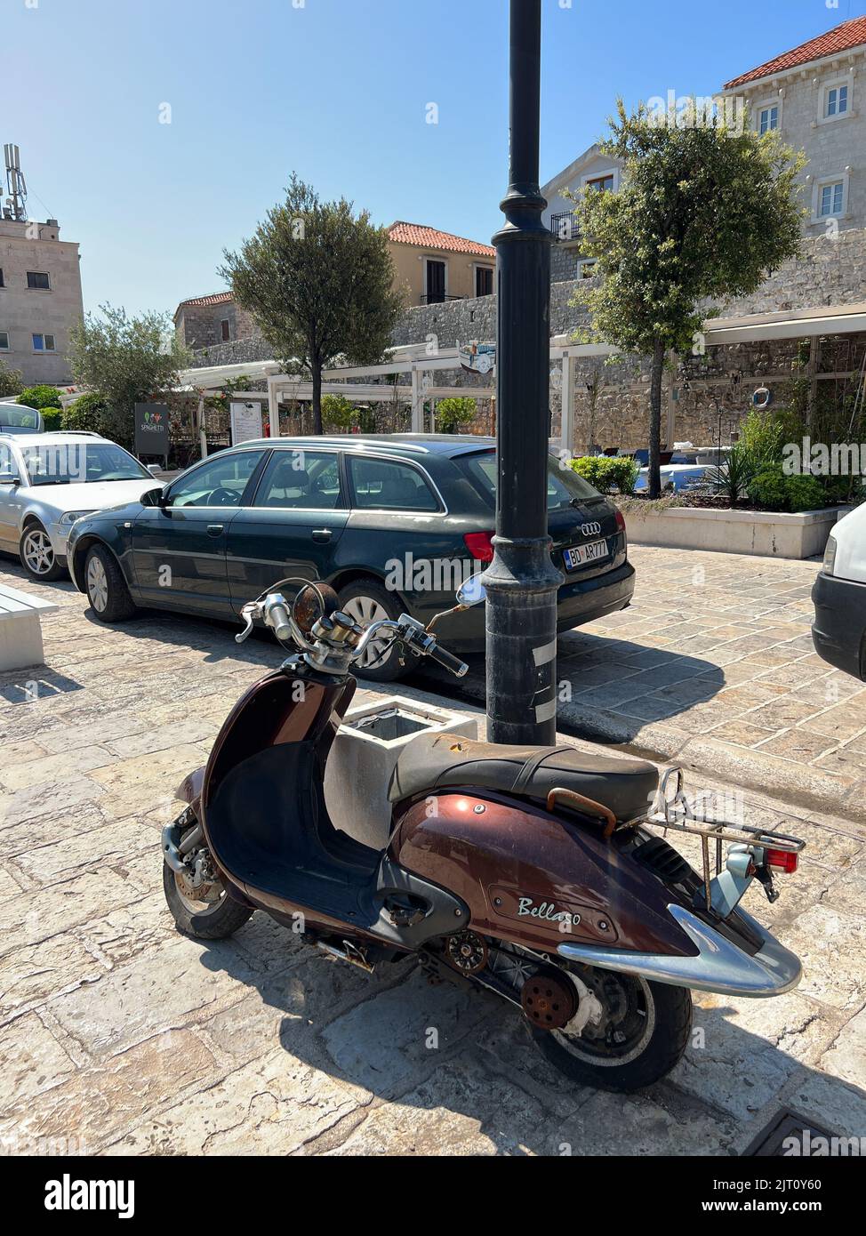 Budva, Montenegro - 01.08.22: Brown scooter parked near a lamp on the ...