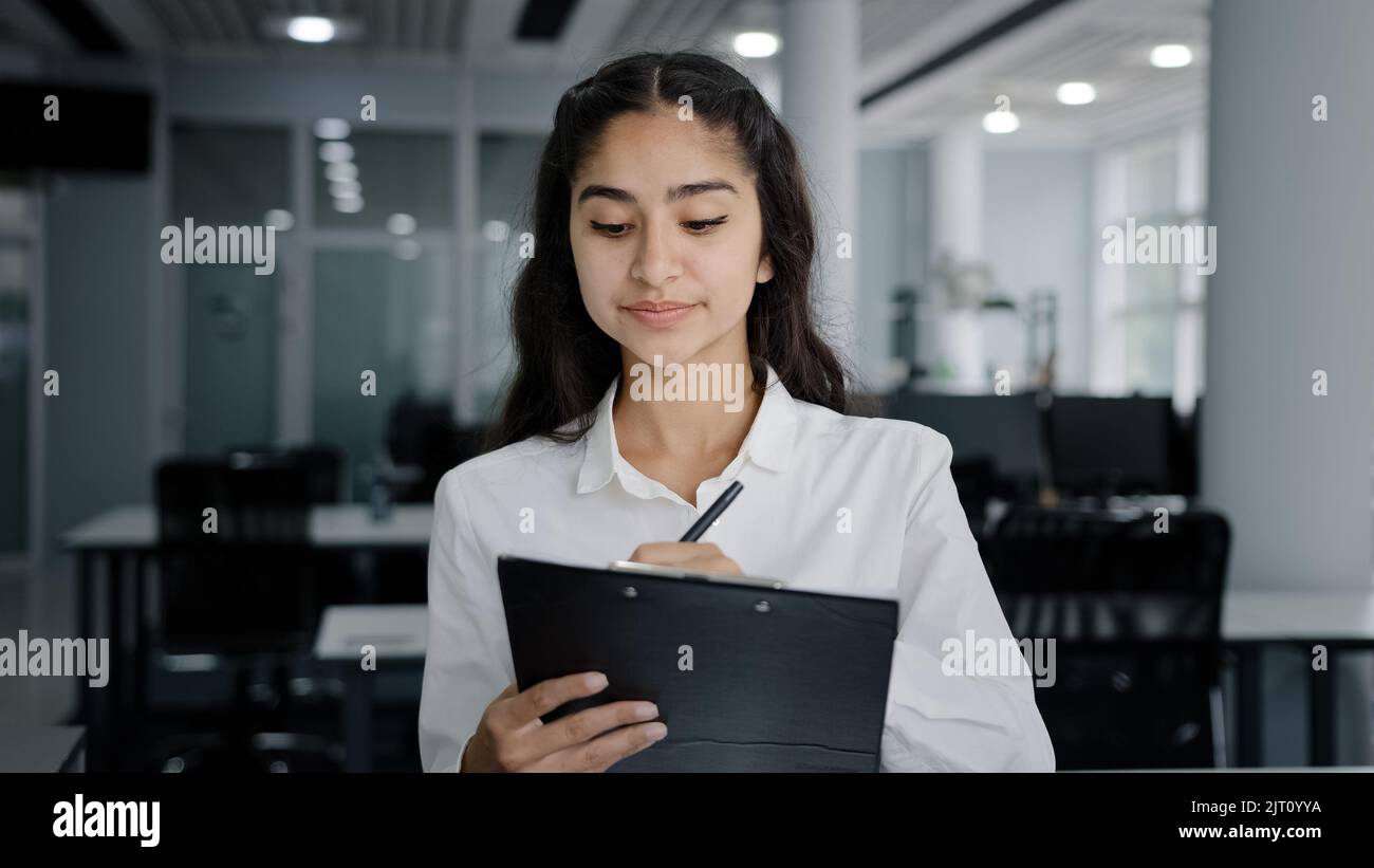 Young woman secretary writes down details of task writing data in ...