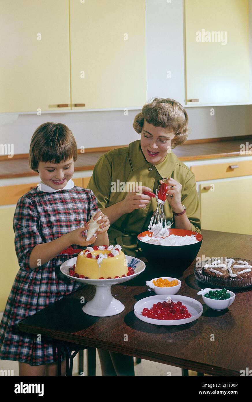 Baking a cake in the 1950s. A mother and her daughter in the kitchen ...