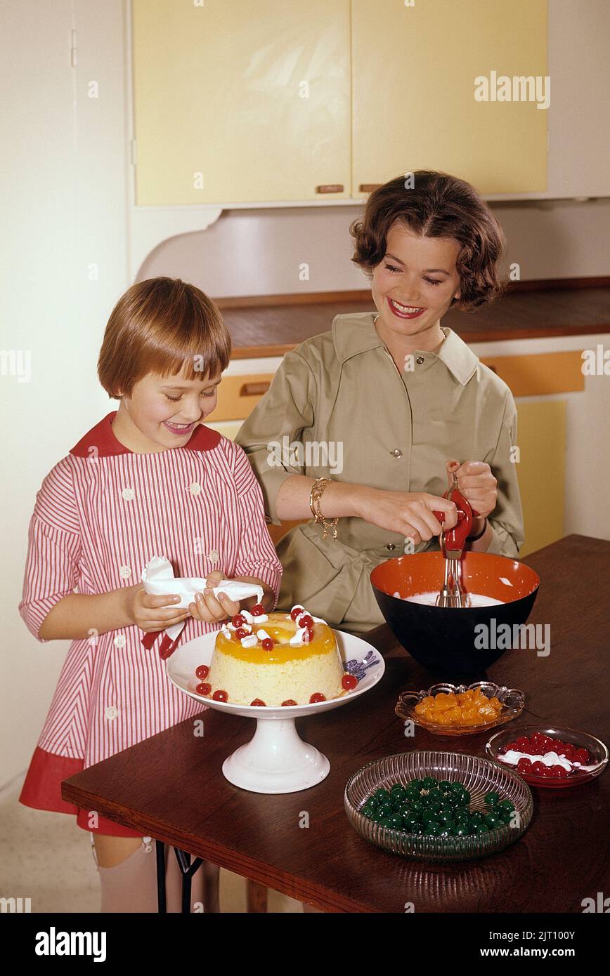 Baking a cake in the 1950s. A mother and her daughter in the kitchen ...