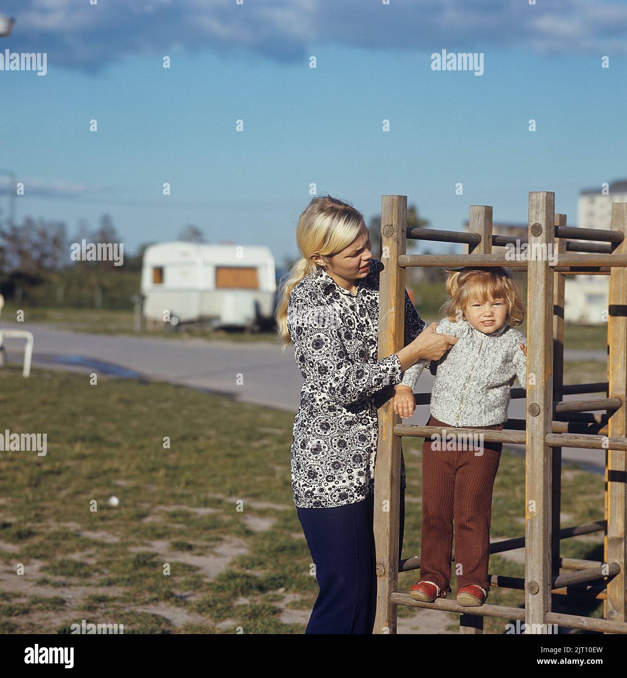 1970s lifestyle. A mother and her daughter are playing on a playground ...
