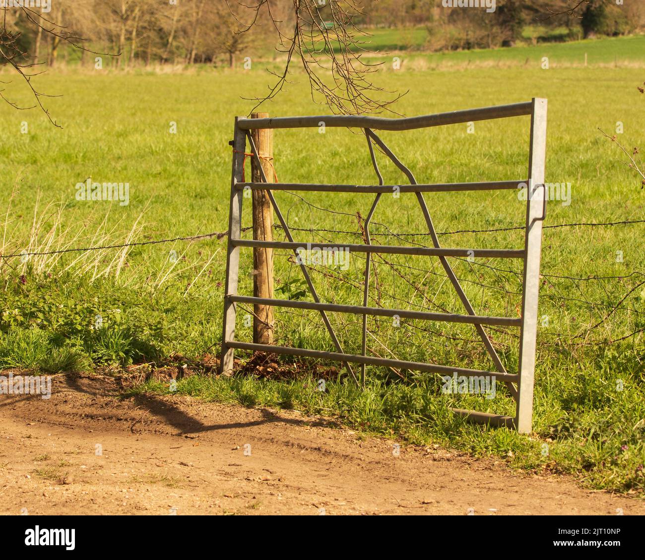 The metal six-bar gate leaned against a barbed wire fence Stock Photo ...