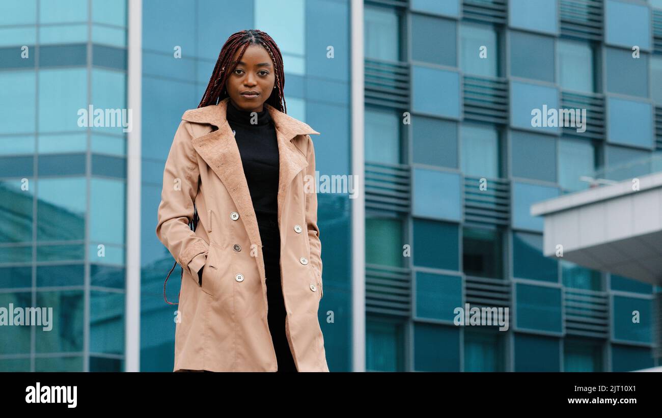 Young stylish woman looks away waiting for meeting stands in business ...