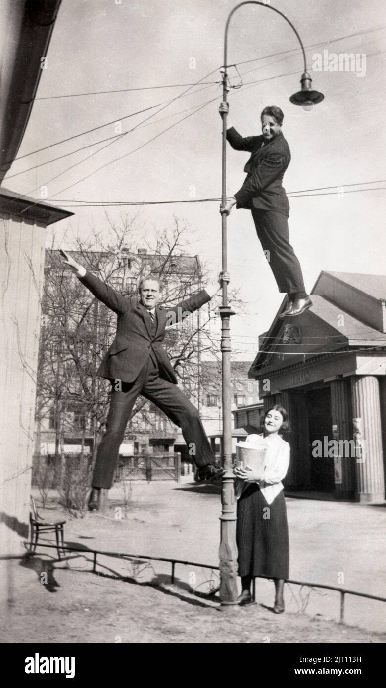 Acrobatic in the 1930s. Two men are haning in a lamp post by their ...