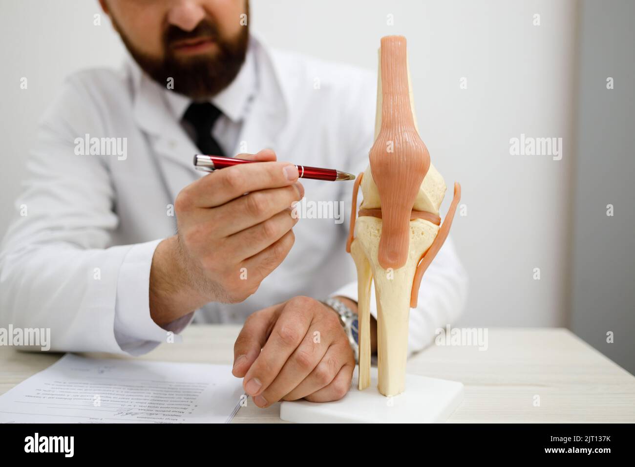 Male doctor shows model of human artificial knee joint in medical ...