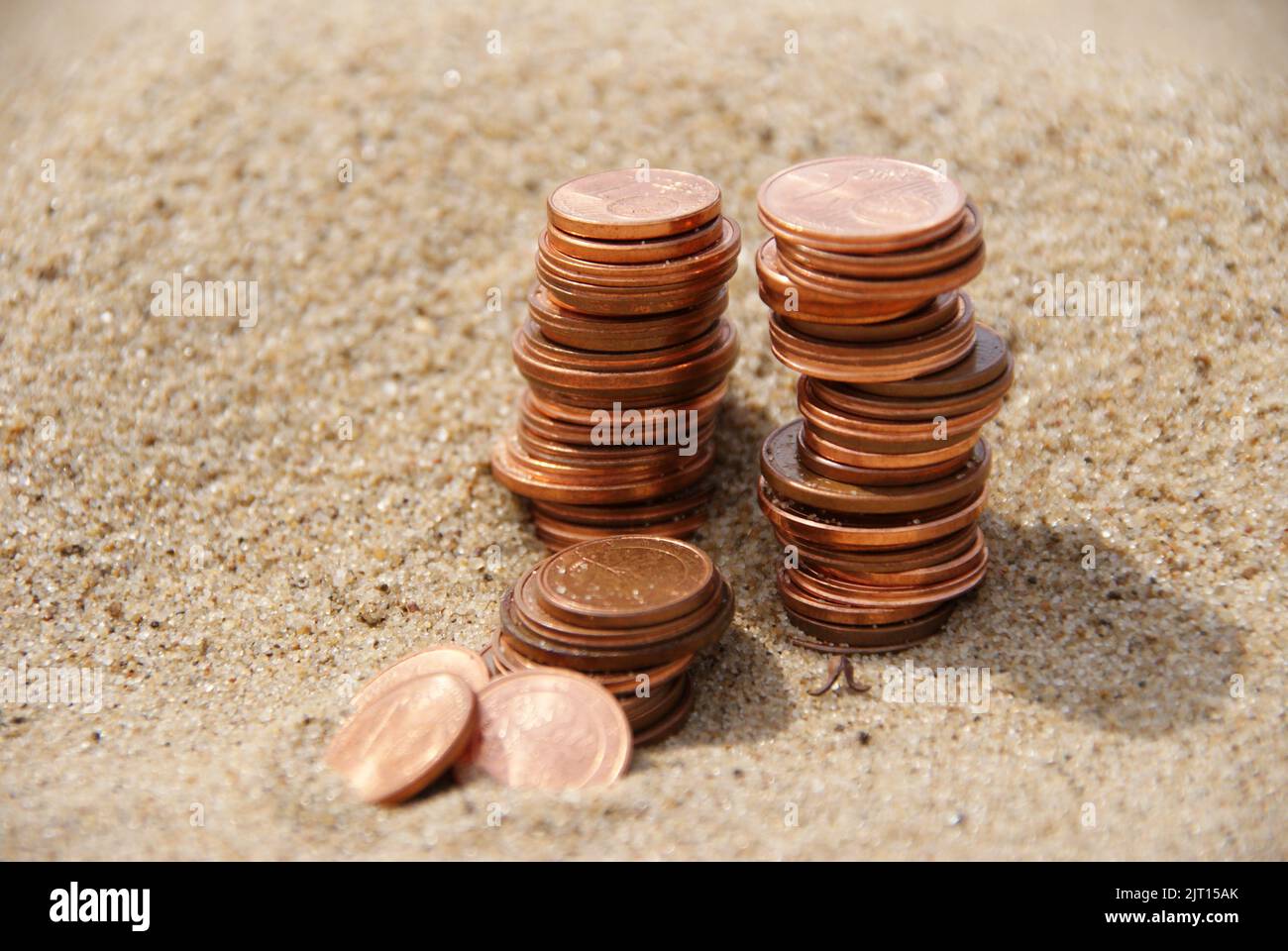 A close-up shot of golden coins stacked on a sand, financial oc Stock ...