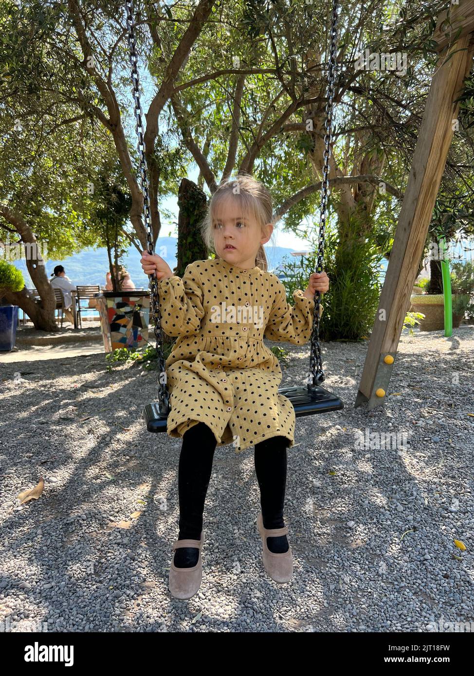 Little girl sits on a chain swing Stock Photo - Alamy