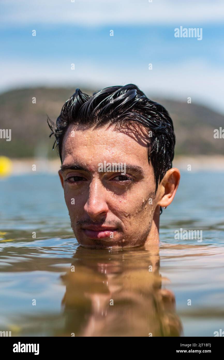 Handsome Caucasian man submerged in water. He is on a beach and his ...