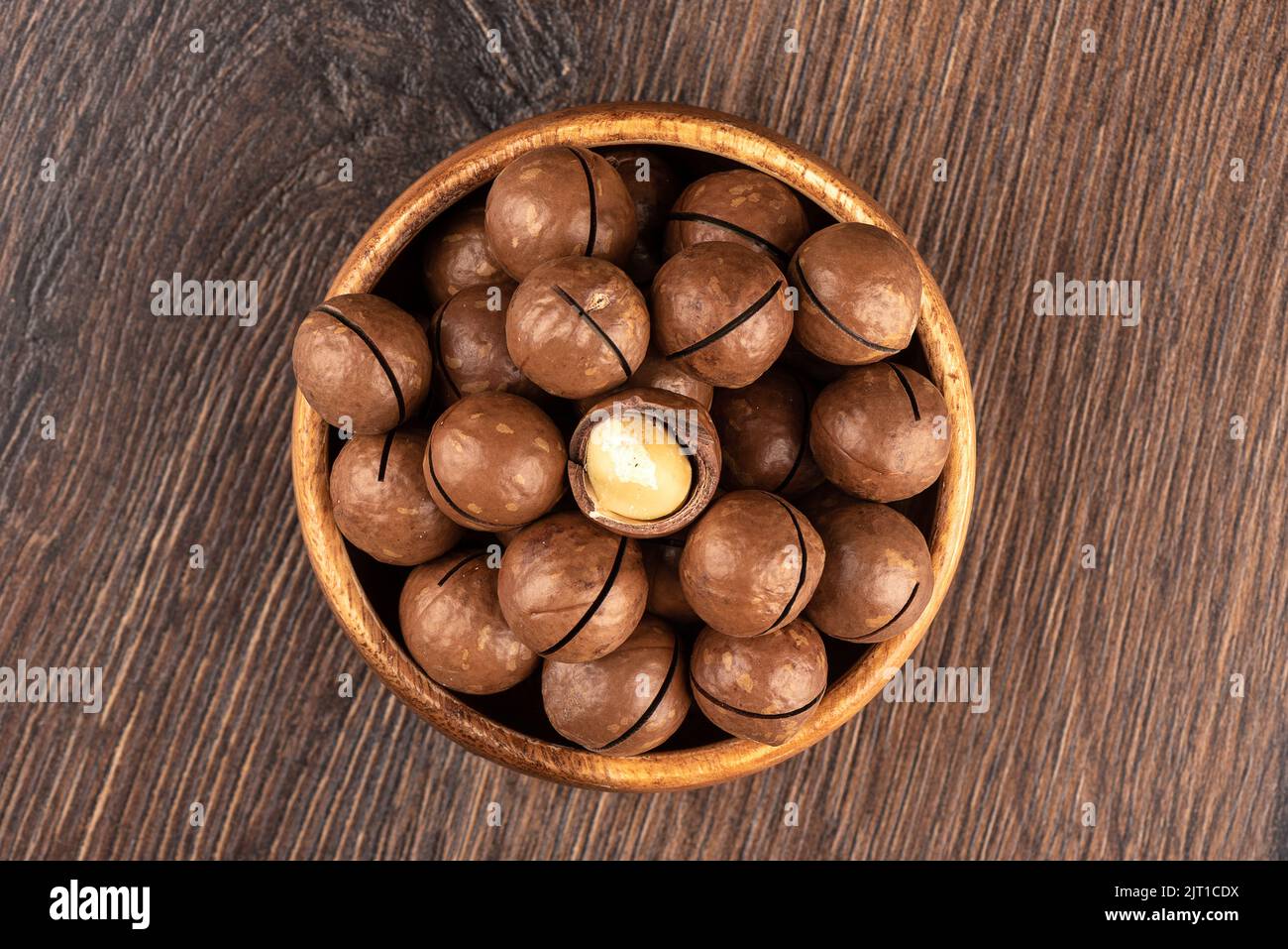 Macadamia nuts in shell and without in a wooden bowl. Top view, copy ...