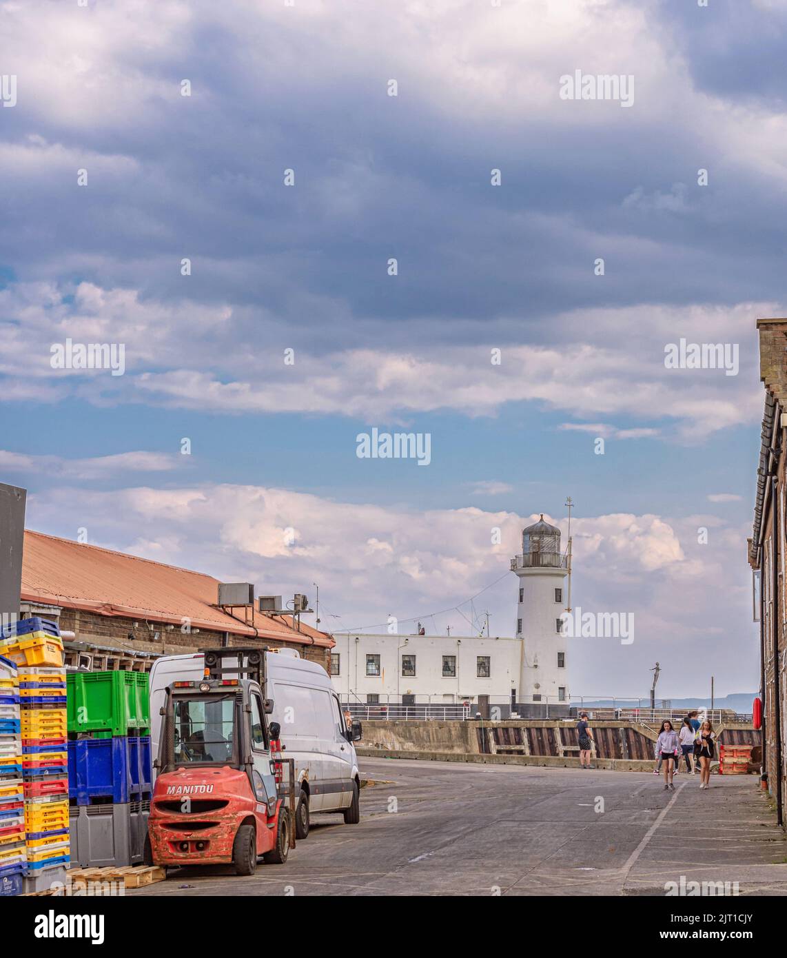 A lighthouse can be seen from between the buildings of a wharf ...
