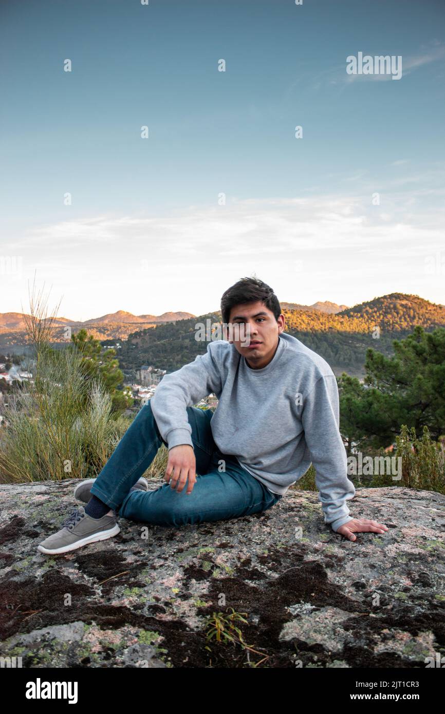 Latin american handsome guy sitting in rock in nature. With the ...