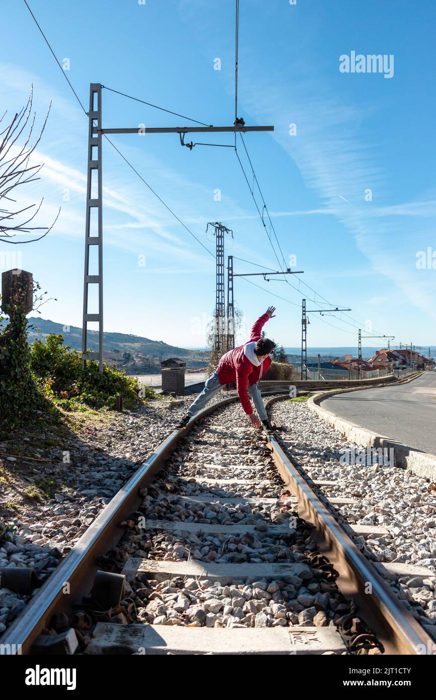 Man stretching in the rail track with a red coat Stock Photo - Alamy
