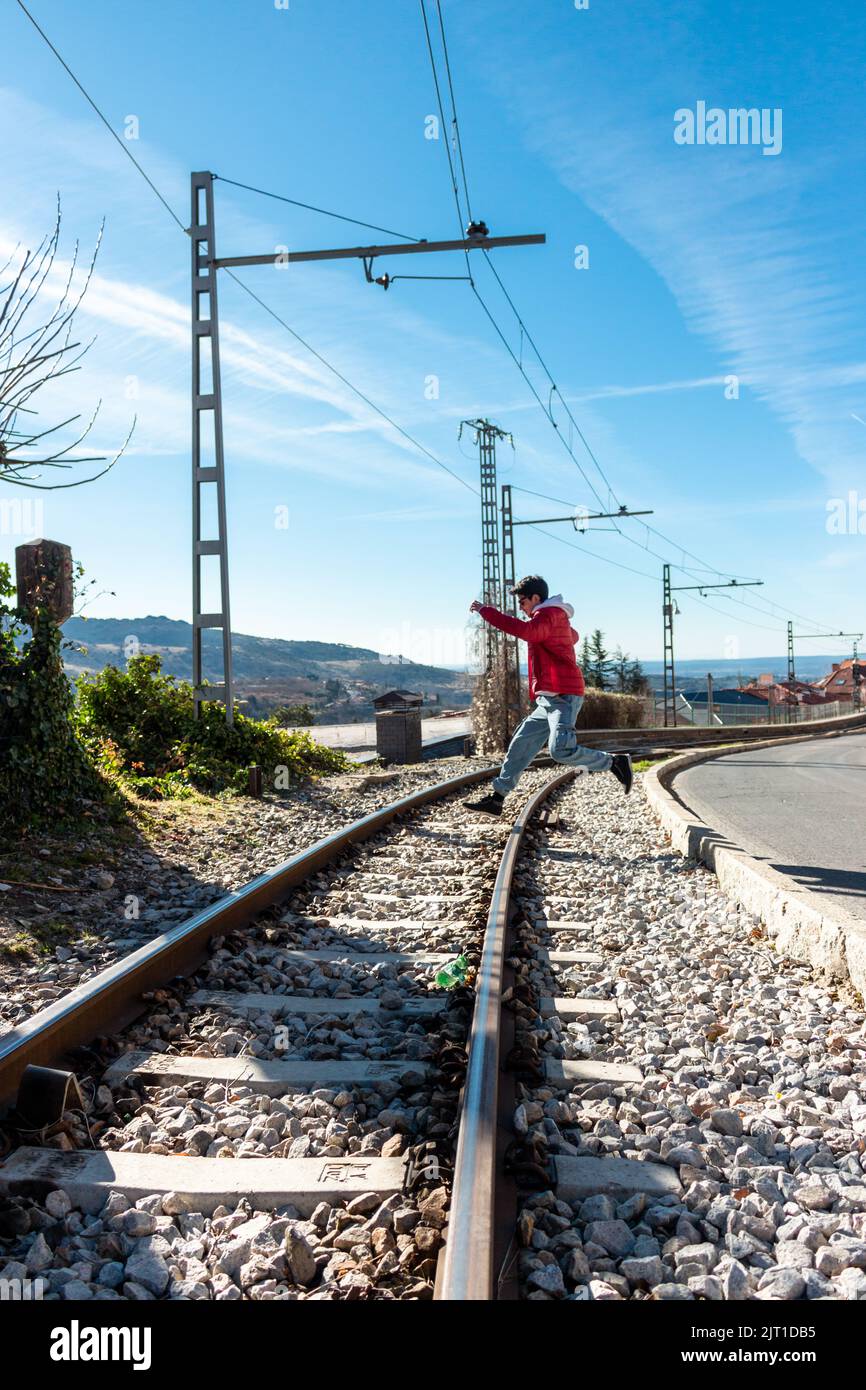Man stretching in the rail track with a red coat Stock Photo - Alamy