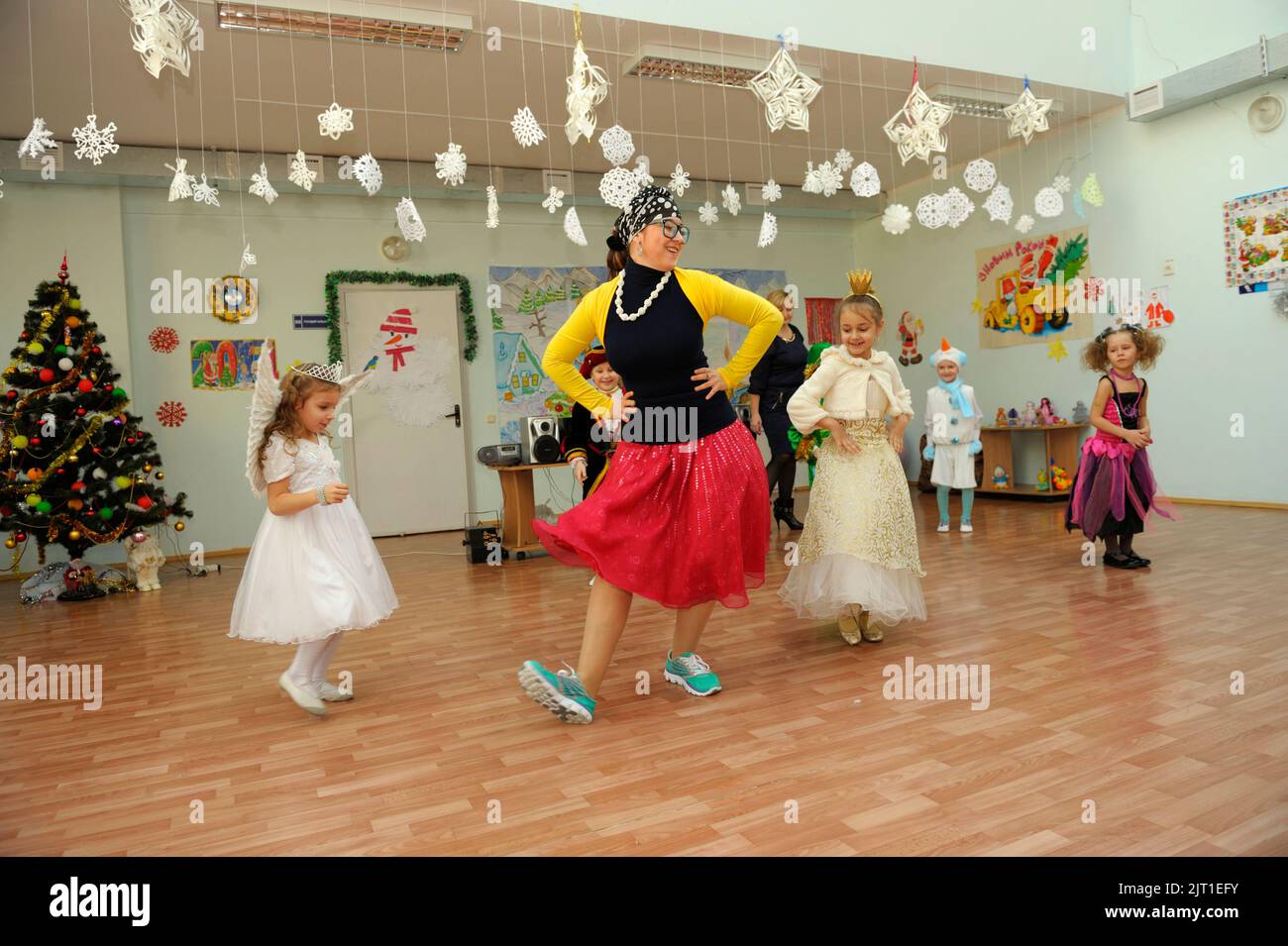 Children and young cheerful woman host in carnival costumes dancing ...