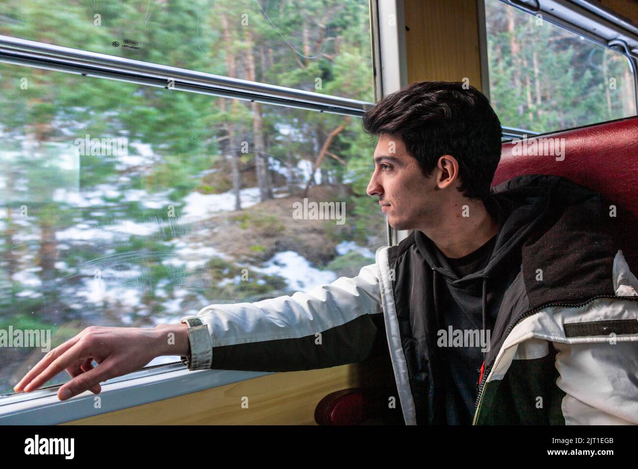 Caucasian handsome man looking out the window while traveling by train ...
