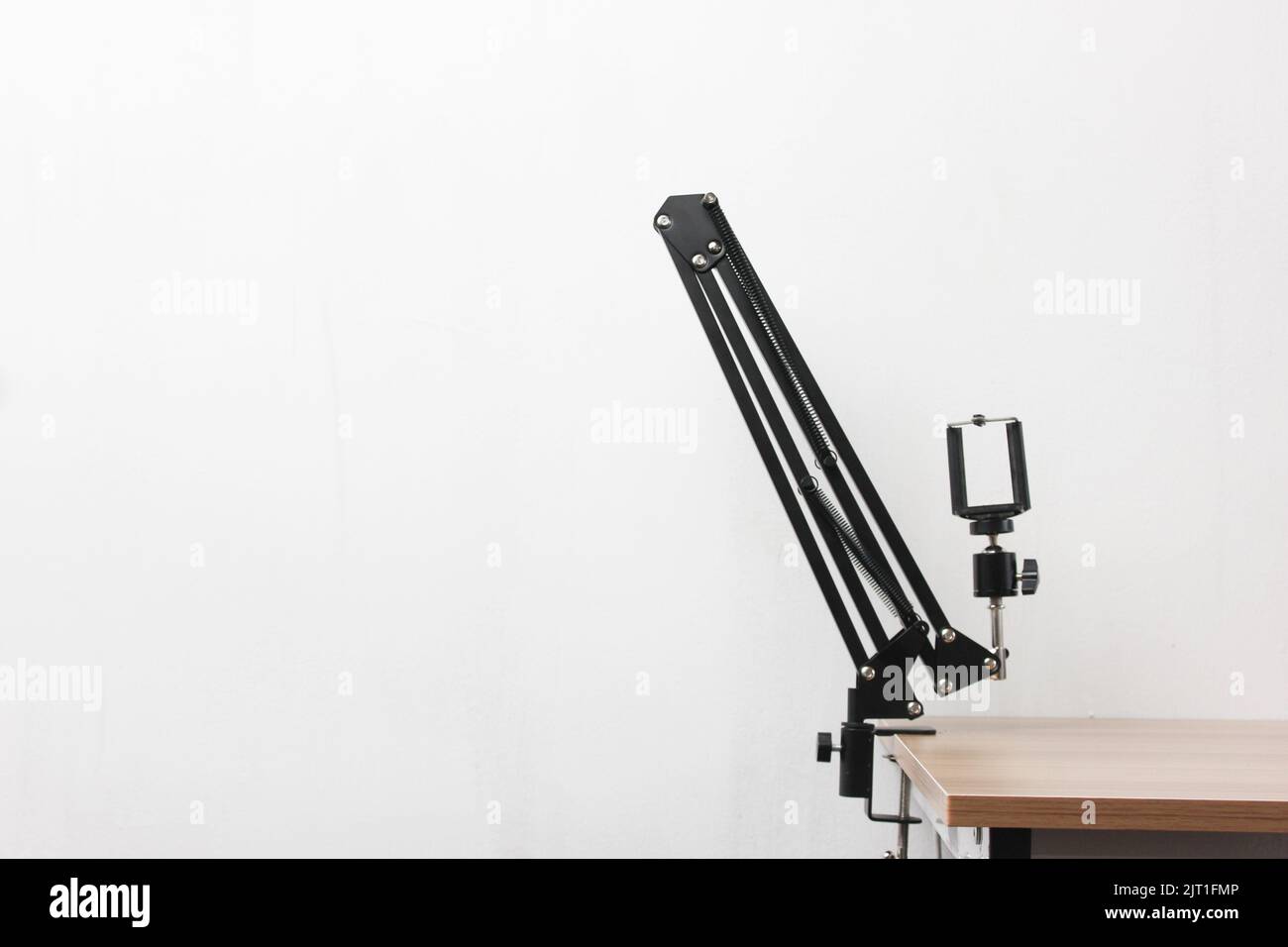 A picture of a camera stand on a wooden table in front of a white wall ...