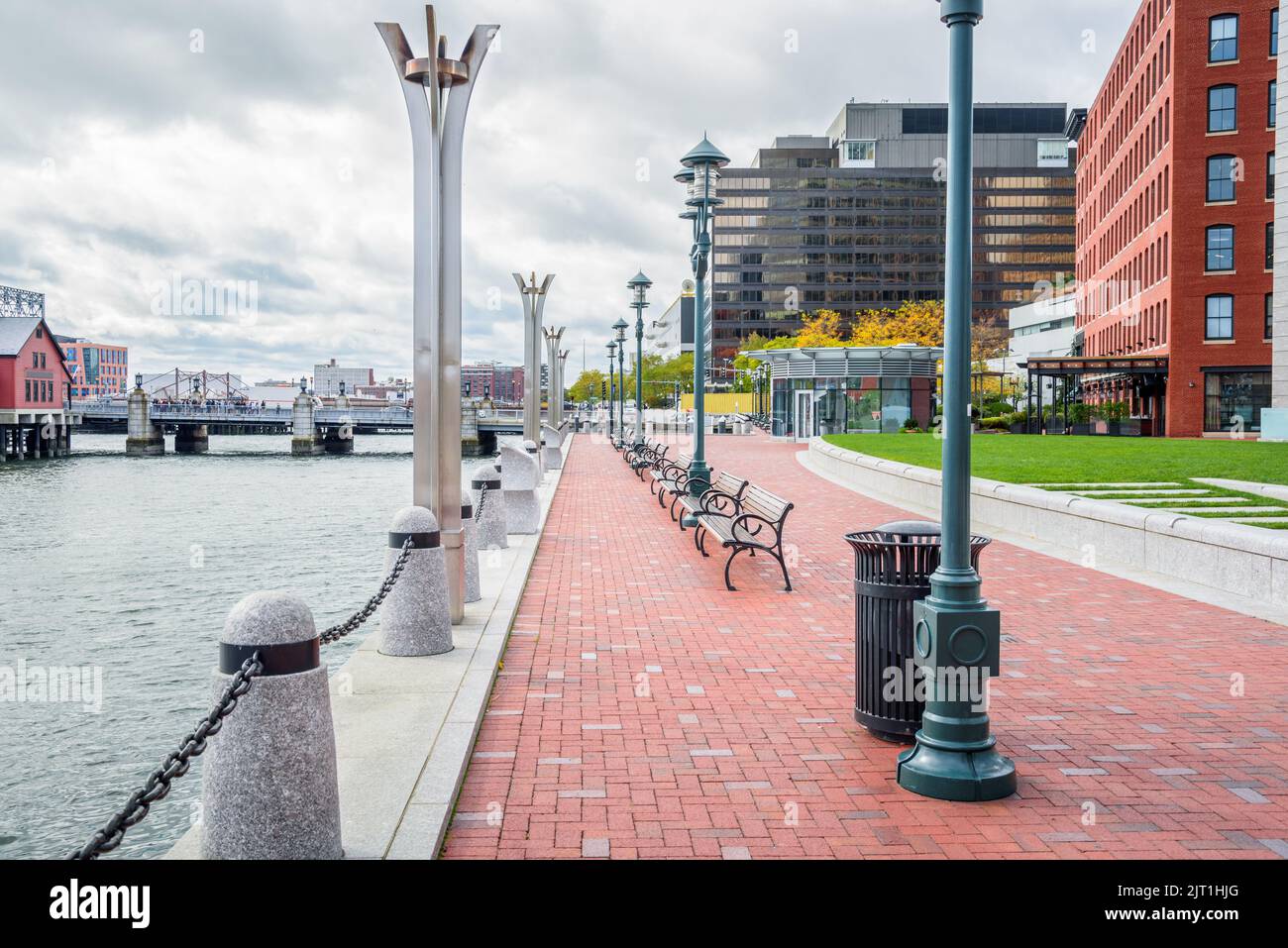 Empty brick waterfront path lined with benches and lamp posts on a ...
