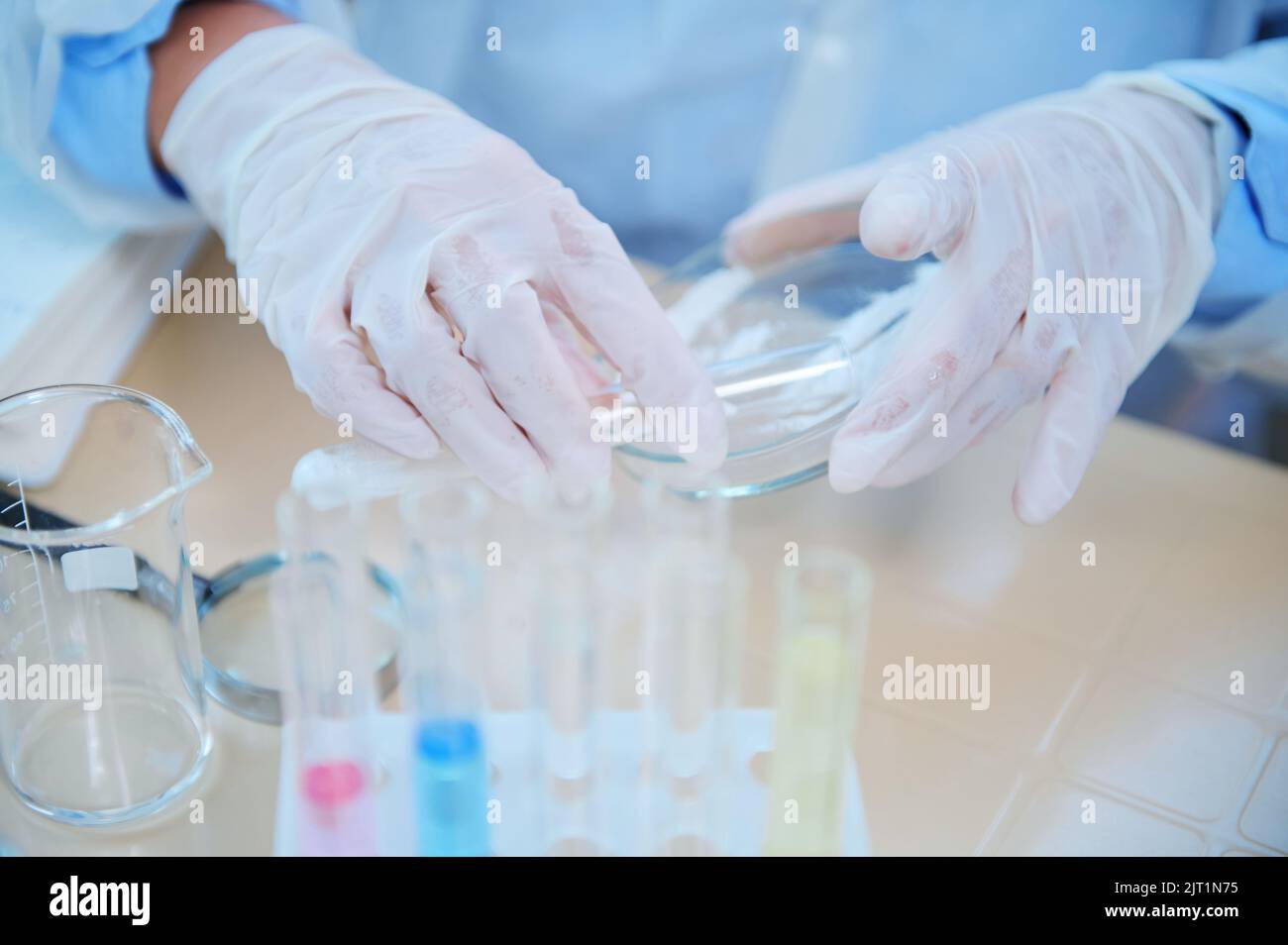 Focus on the hands in protective gloves of a lab assistant, pouring ...