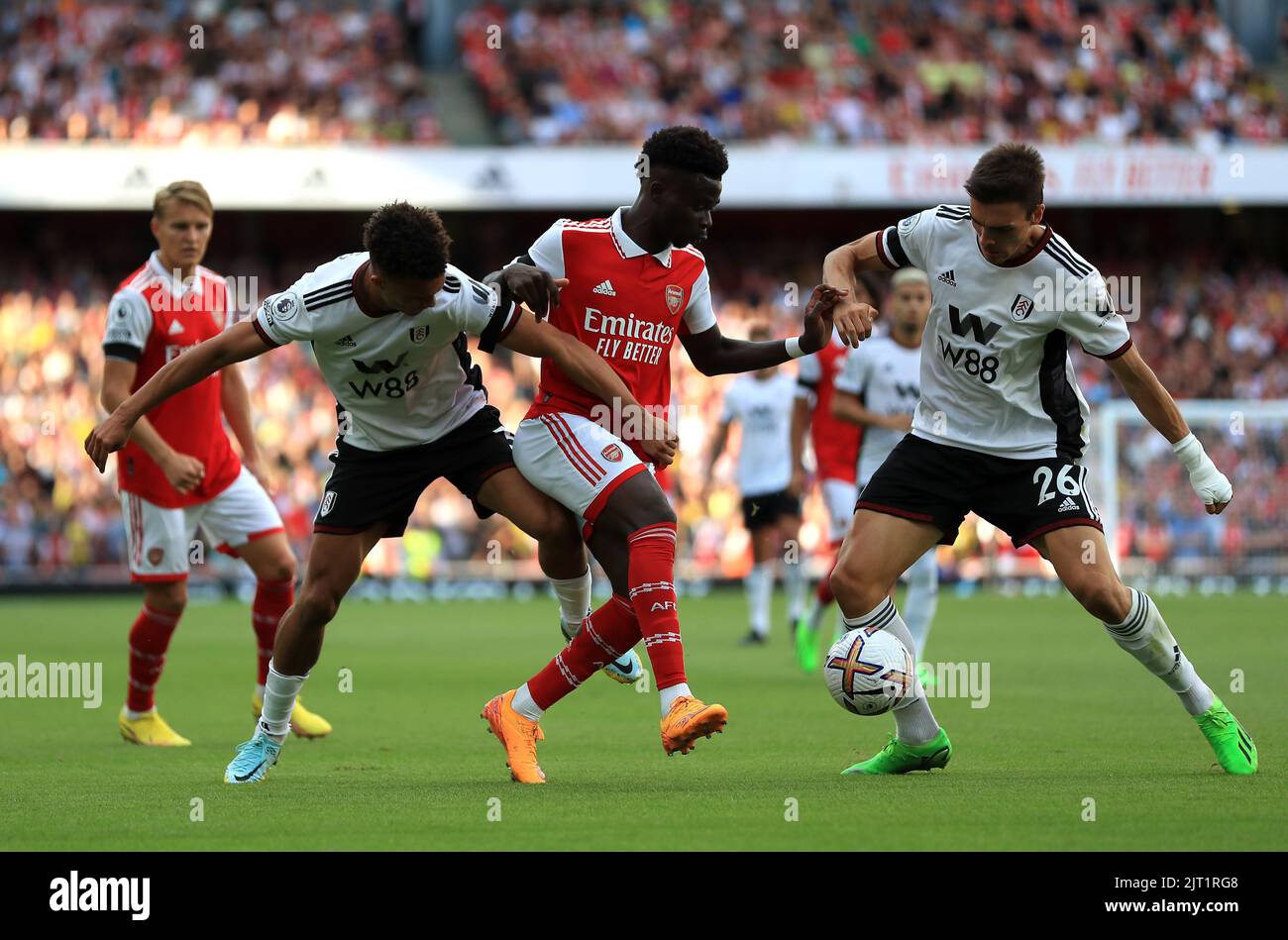 Arsenal's Bukayo Saka (centre) battles for the ball with Fulham's Antonee Robinson (left) and ...