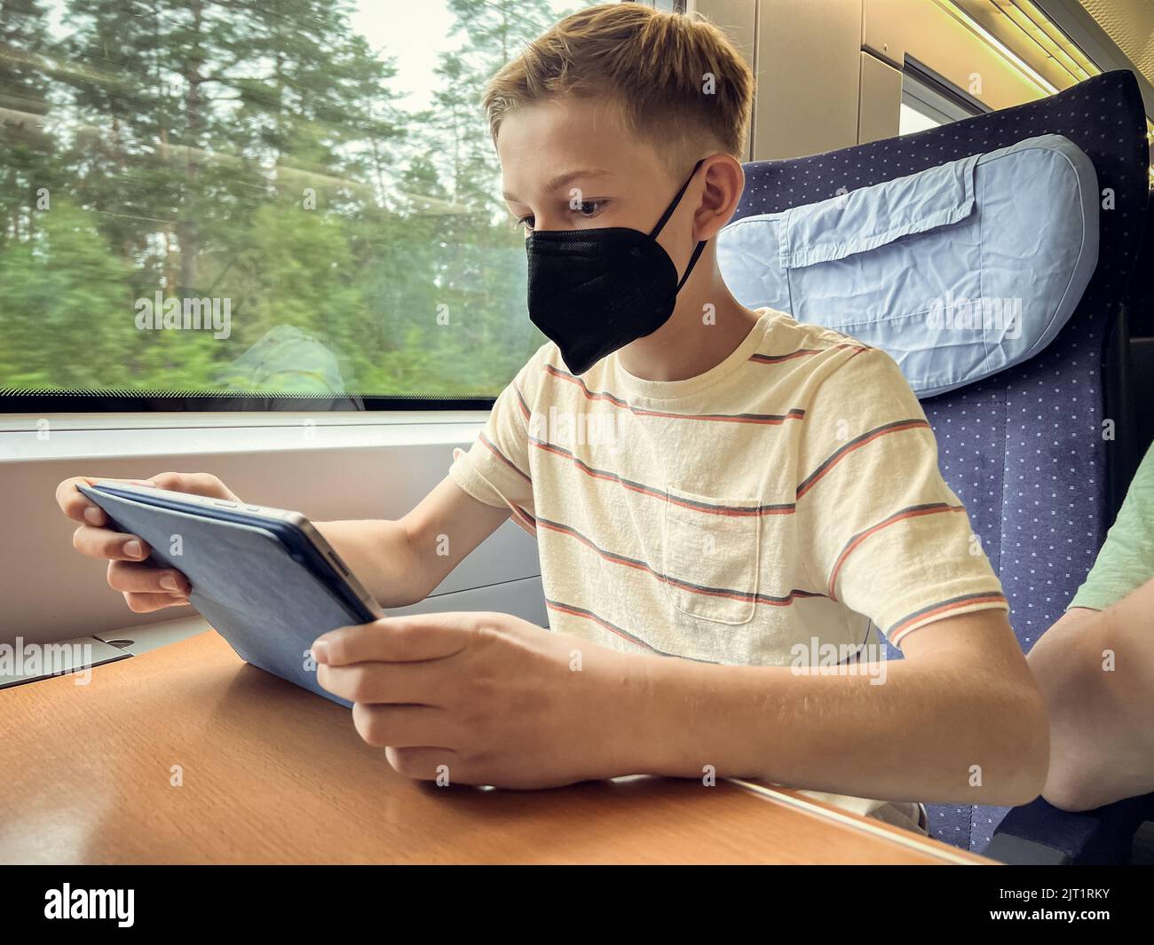 Teen boy playing tablet during his train journey on vacation Stock ...