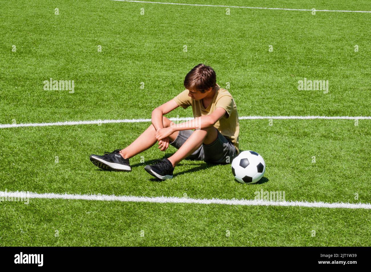 Sad alone teenage boy sitting in empty school sport stadium outdoors ...