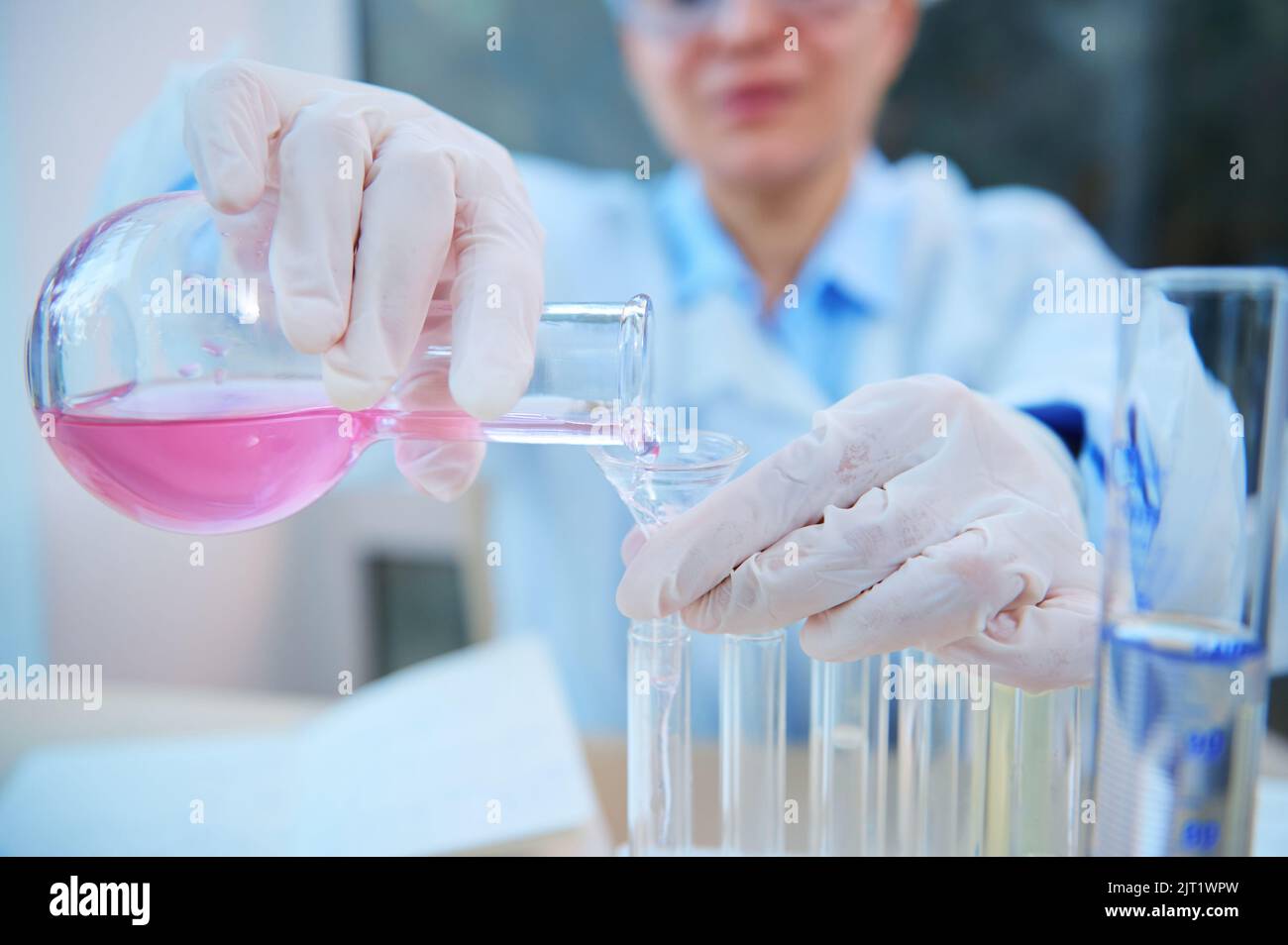 Focus on a glass laboratory flask in the hands of blurred scientist ...