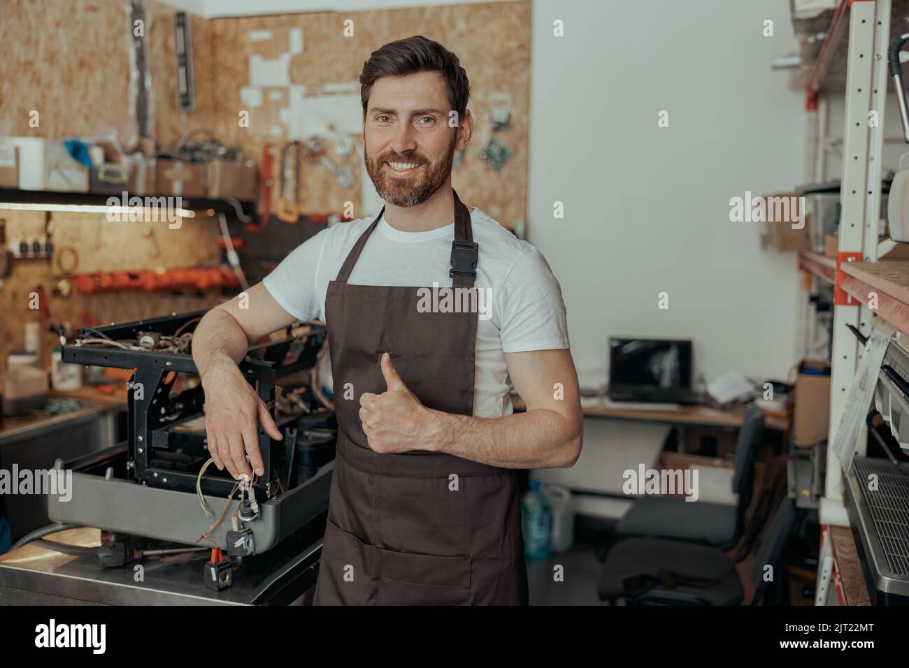 Repairman in uniform standing on workshop of coffee machines warehouse ...