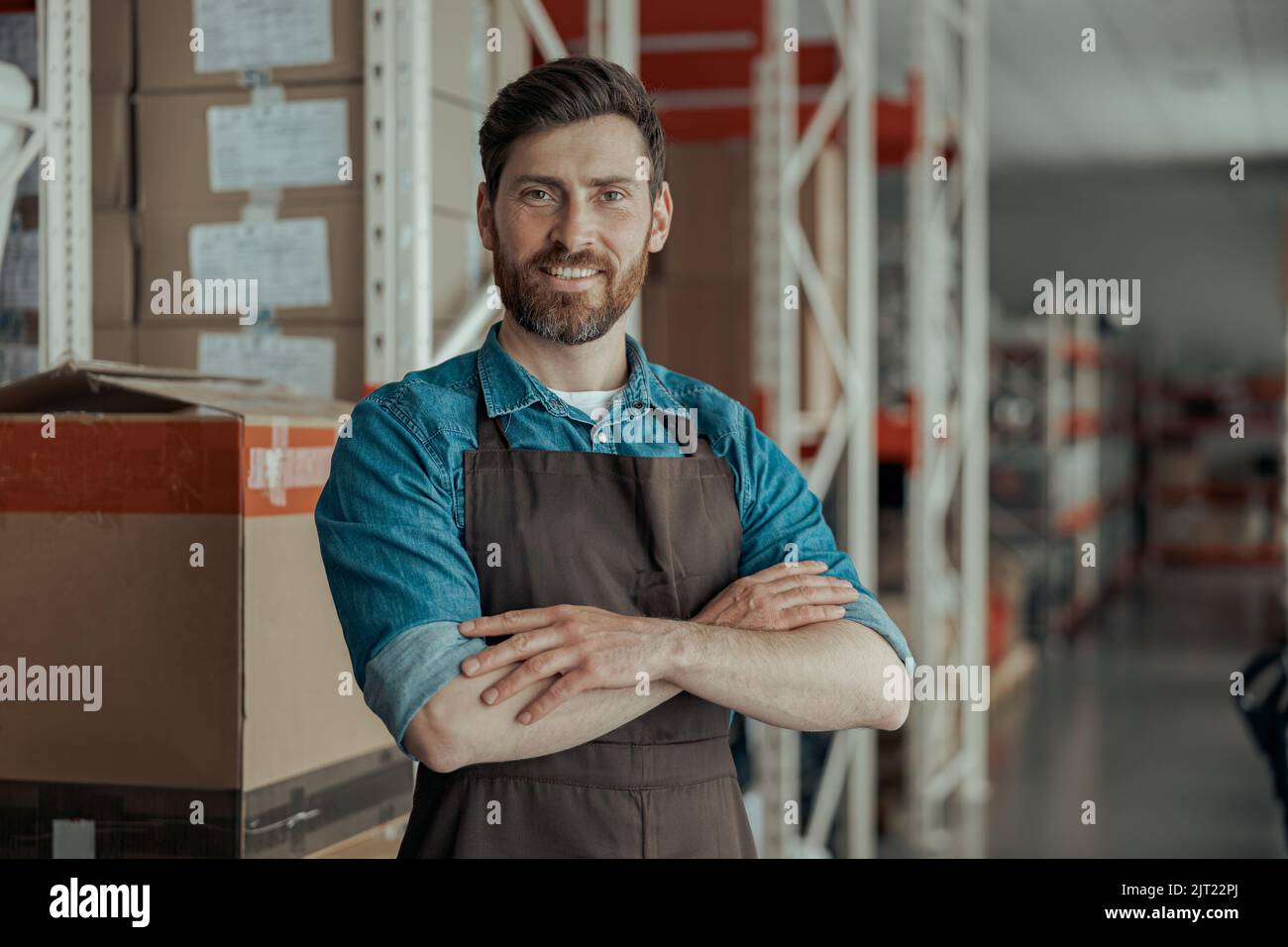 Portrait of smiling business owner standing on warehouse of own small ...