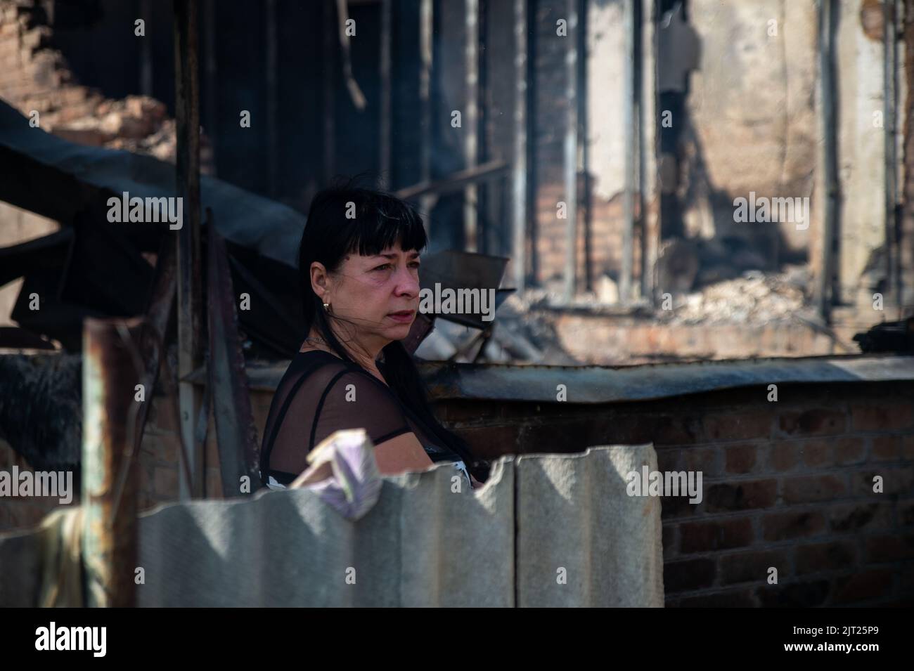 Olia stands among the smoldering remnants of her house destroyed by ...