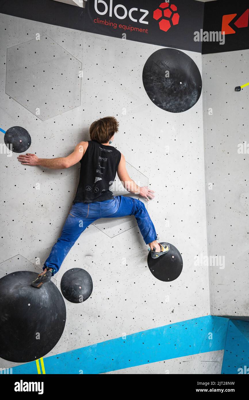 A strong athlete climbing on the wall in the bouldering gym of ...