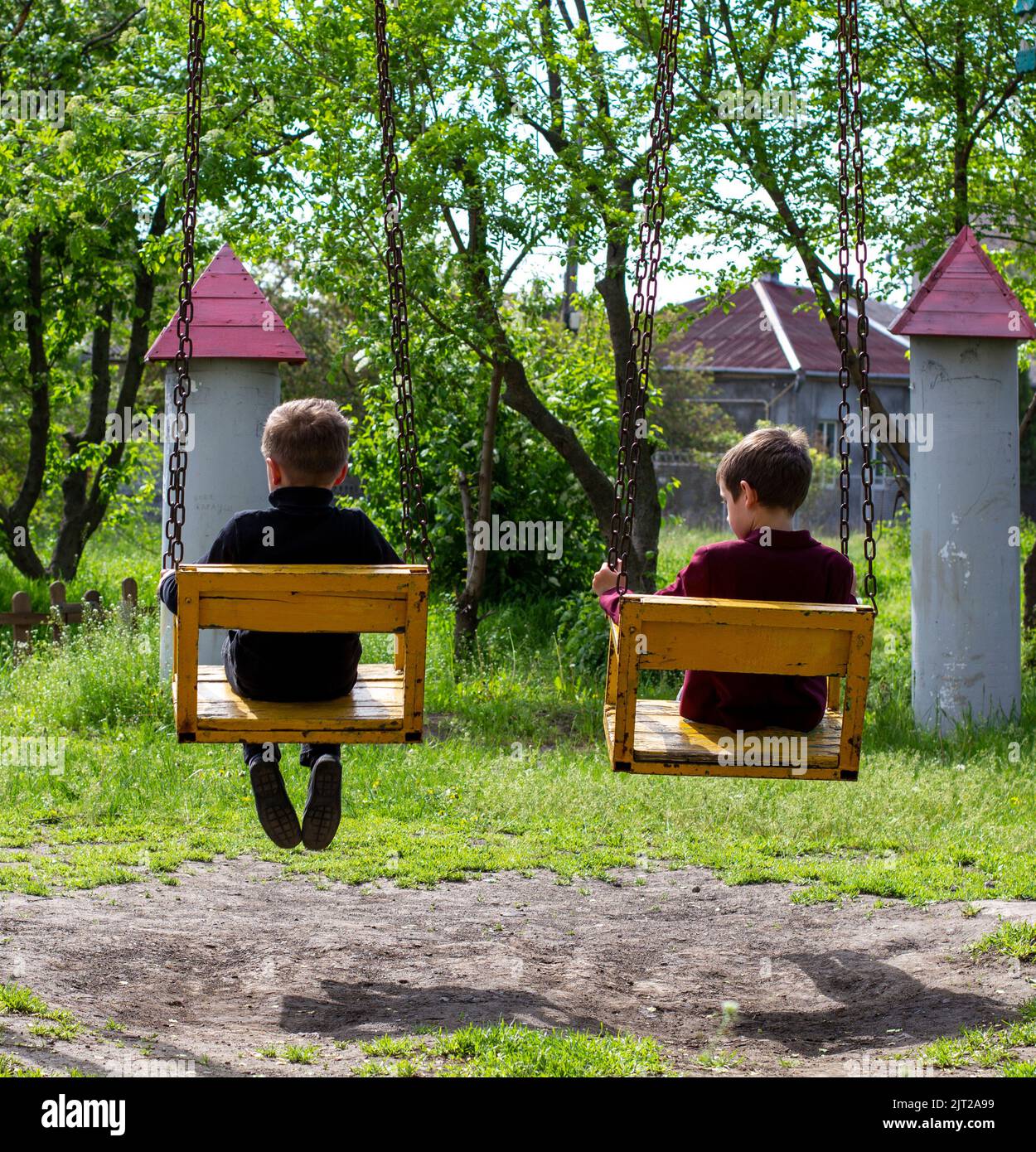 Two cheerful boys ride on swing Stock Photo - Alamy